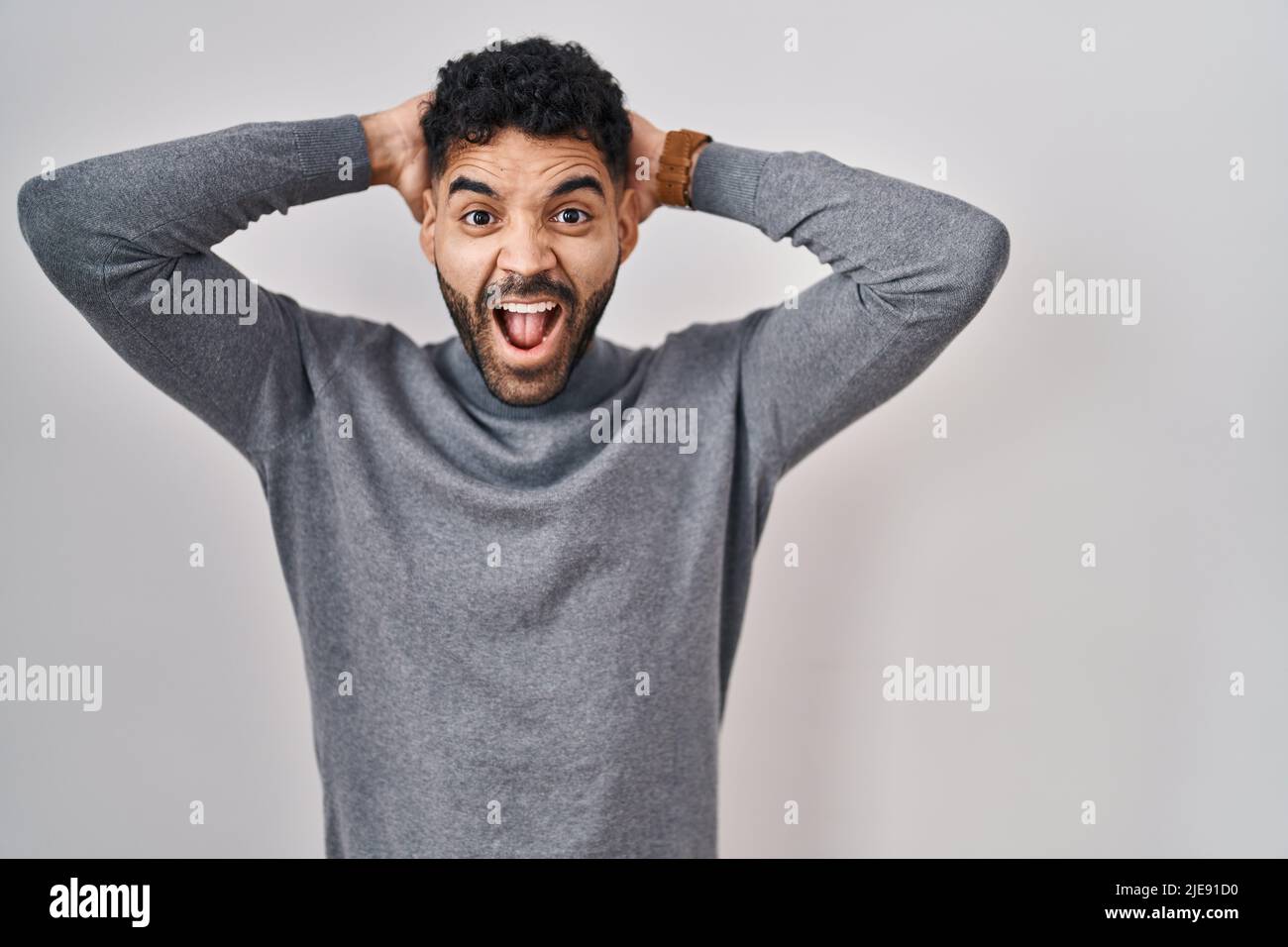 Hispanic man with beard standing over white background crazy and scared ...