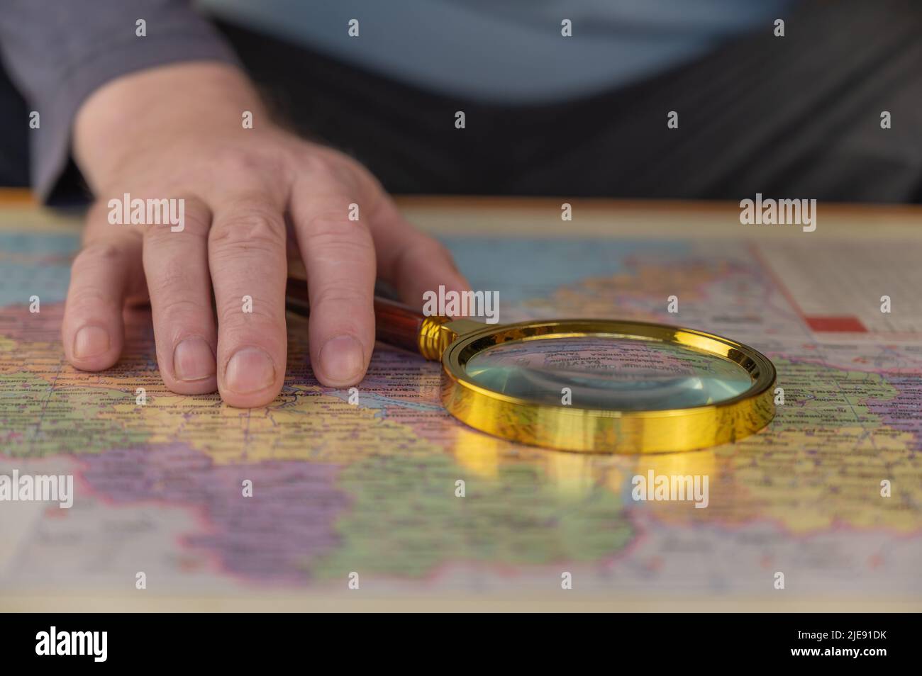 A man holds a magnifying glass in his hand over a map. A middle-aged ...