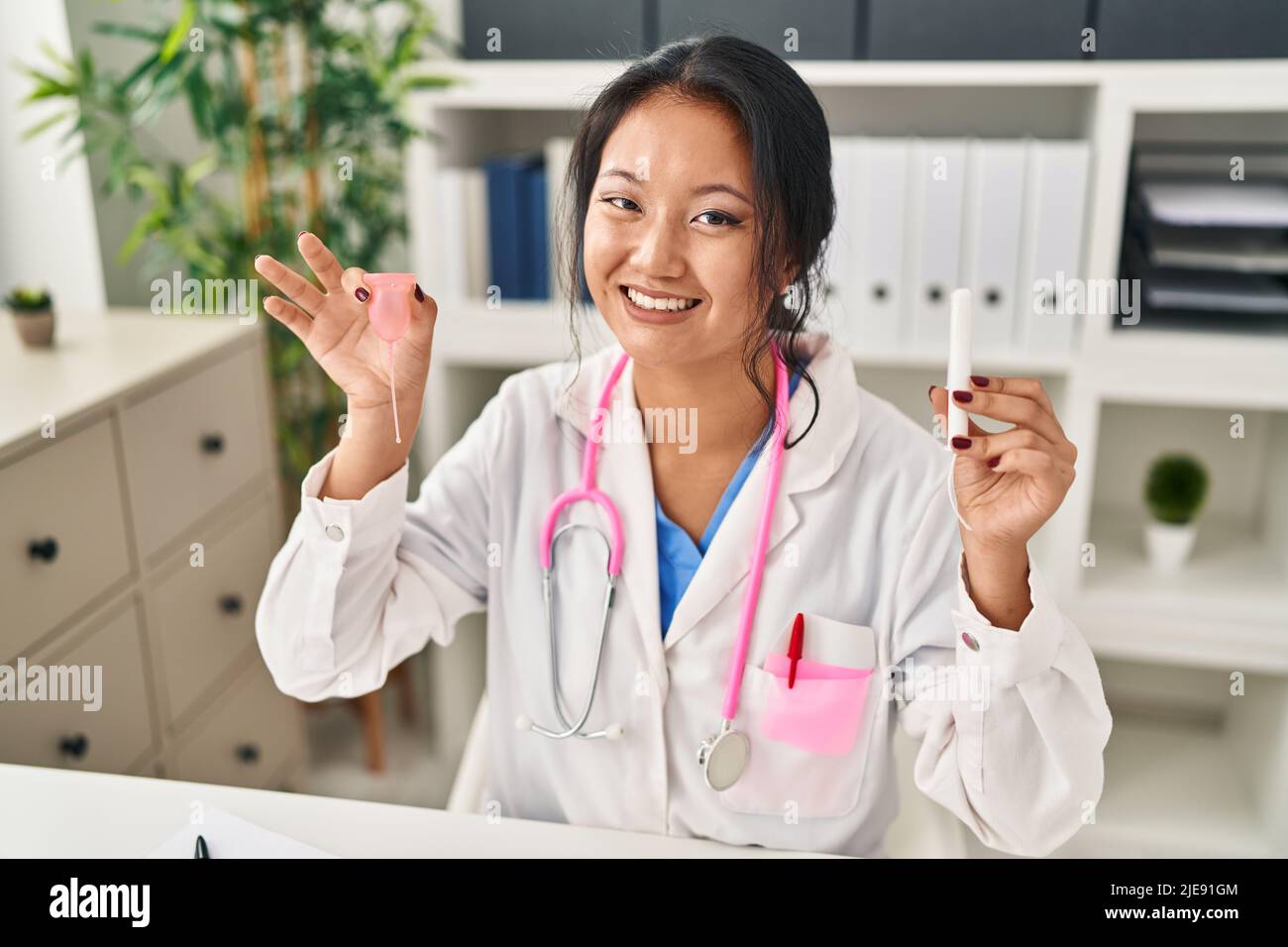 Young asian doctor woman holding menstrual cup and tampon smiling with ...