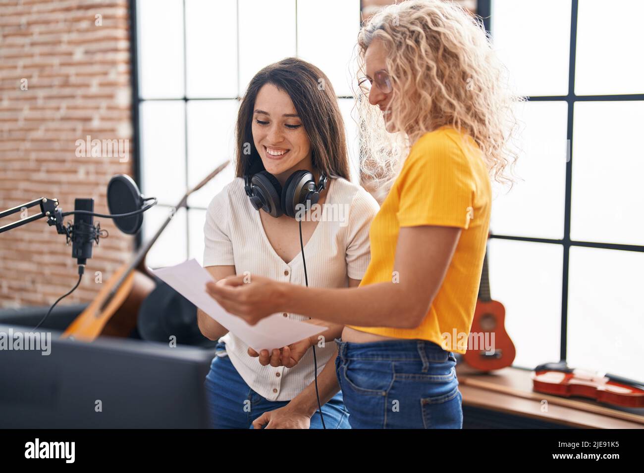 Two women musicians reading music sheet at music studio Stock Photo - Alamy