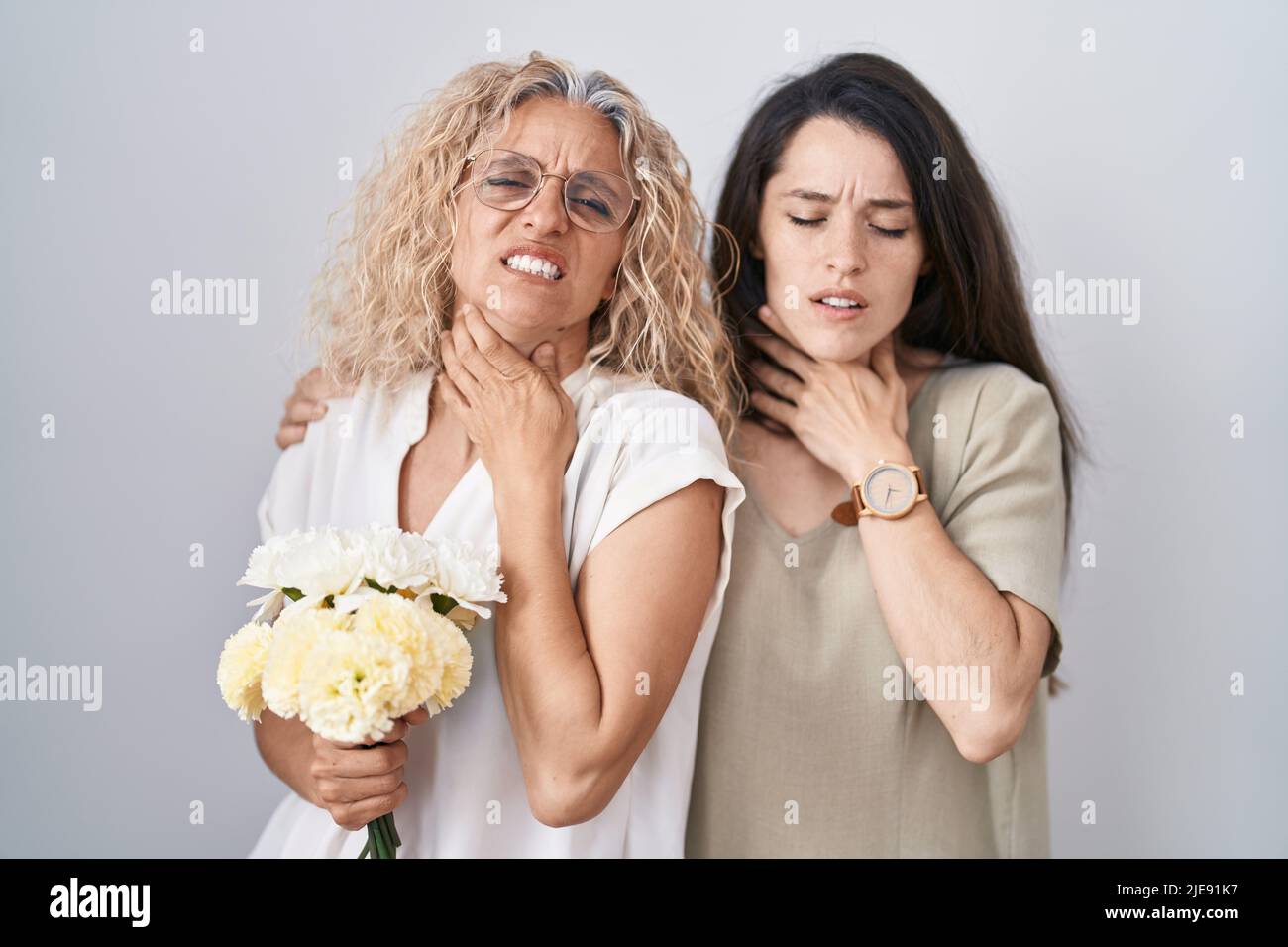 Mother and daughter holding bouquet of white flowers touching painful ...