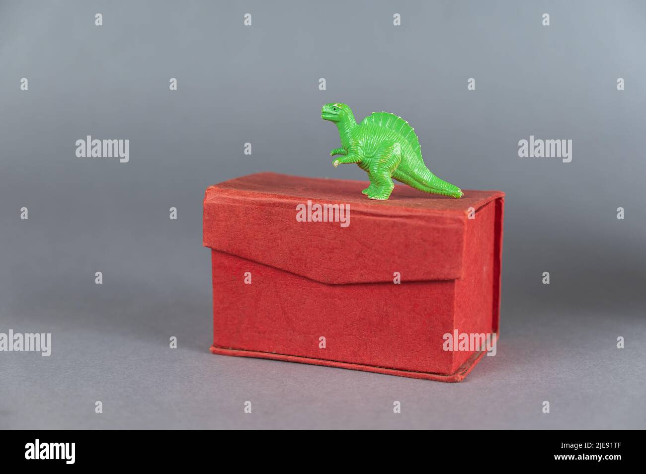 Red box and miniature of one dinosaur against a gray background. Small ...