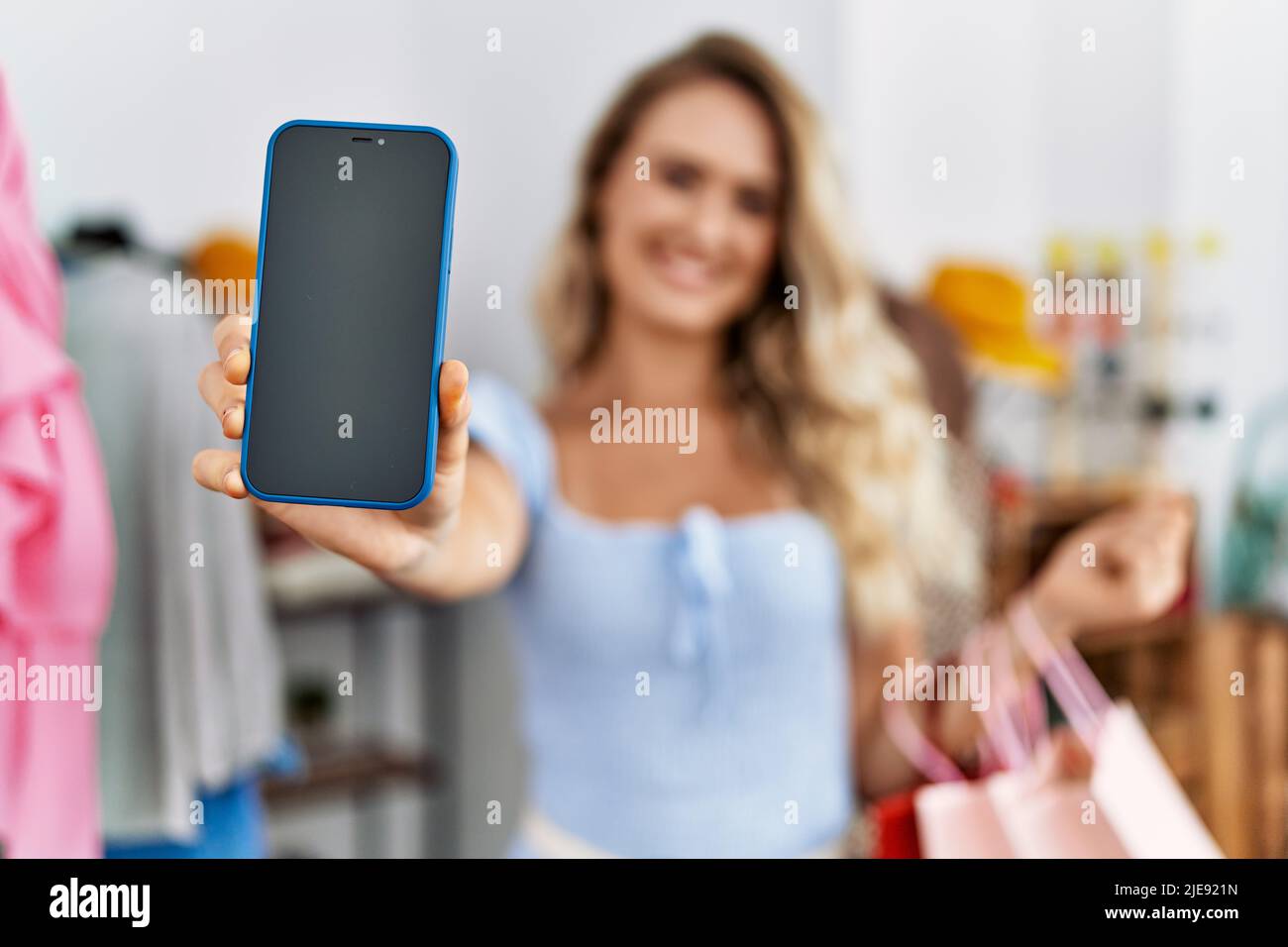 Young woman customer showing smartphone app holding shopping bags at ...