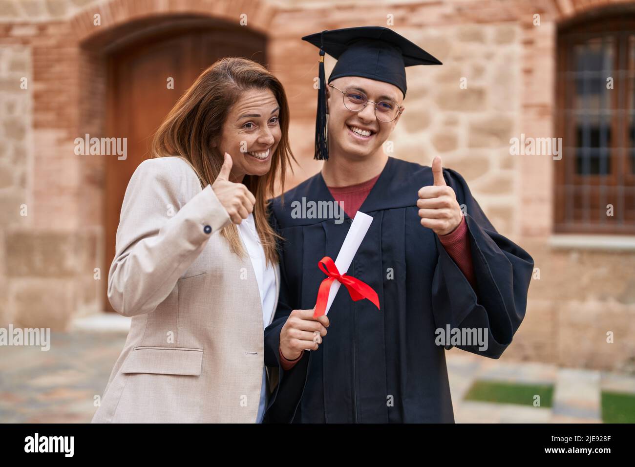 Man and woman mother and son doing ok gesture holding graduate diploma ...