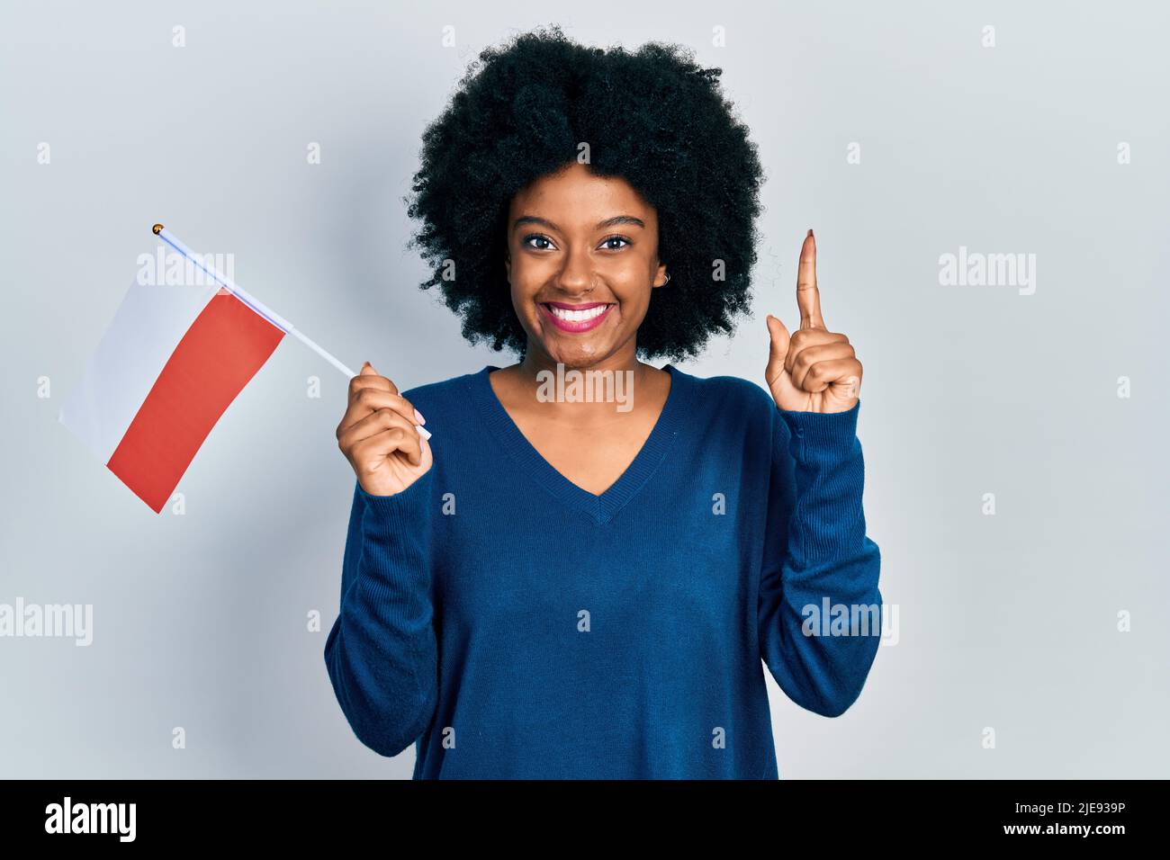 Young african american woman holding poland flag smiling with an idea ...