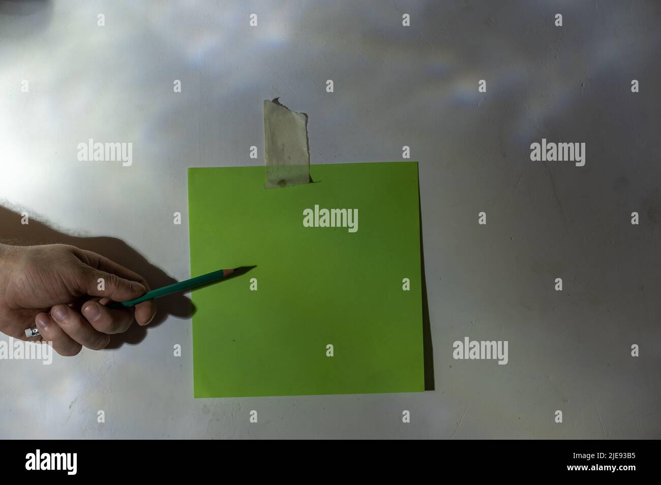 Mature man's hand points to piece of paper with pencil. Empty green ...