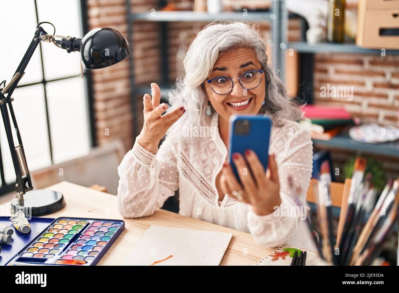 Middle age woman artist drawing on notebook having video call at art ...