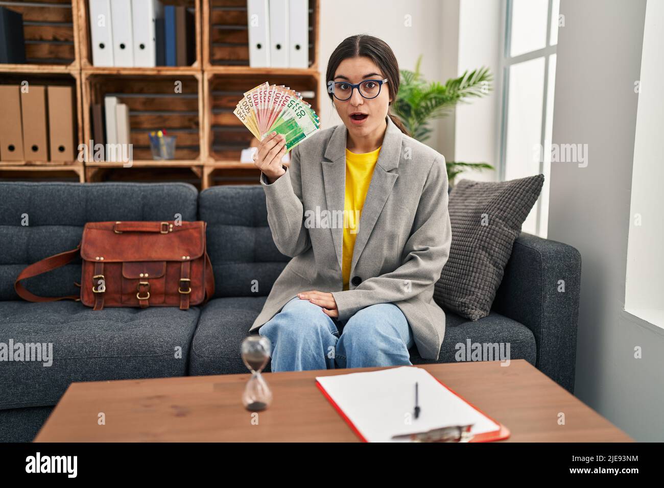 Young hispanic woman working at consultation office holding money ...