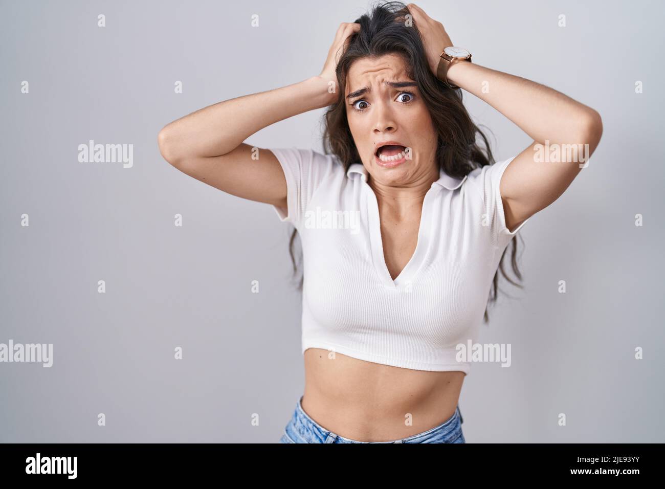 Young teenager girl standing over white background crazy and scared ...