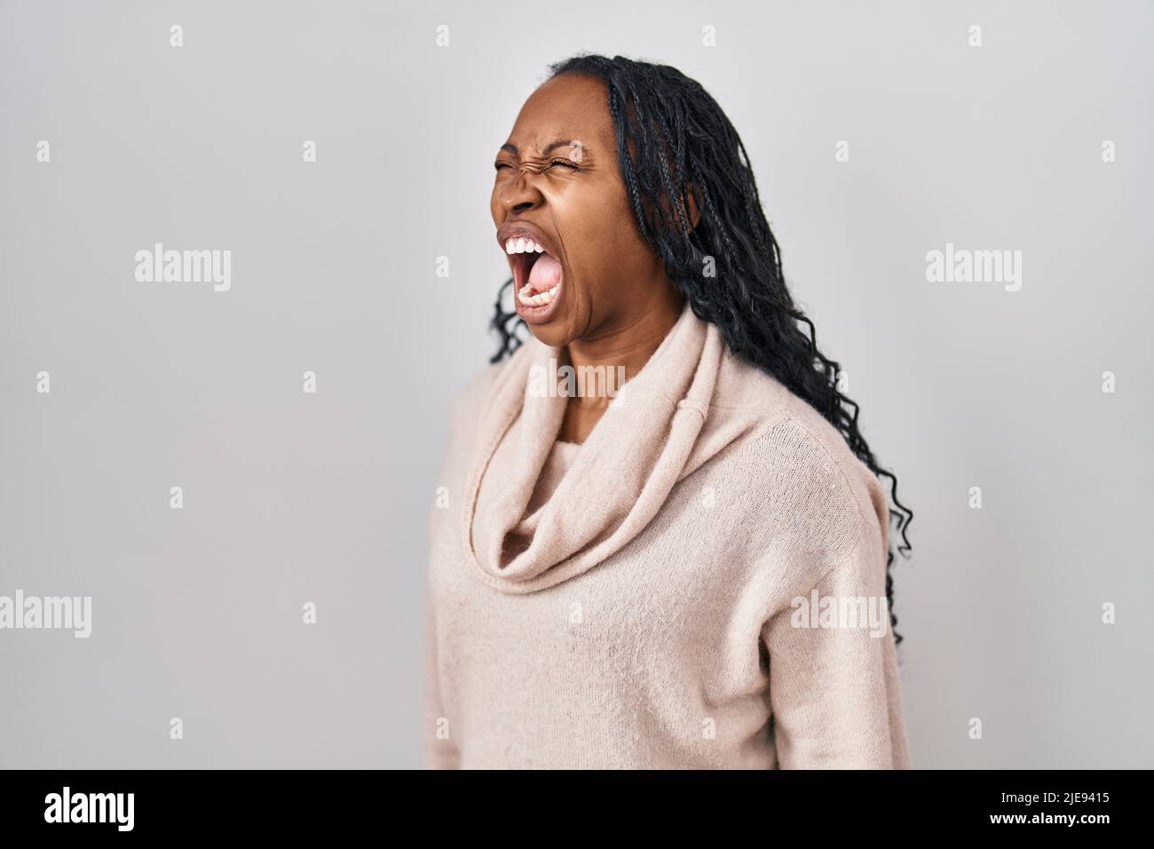 African woman standing over white background angry and mad screaming ...