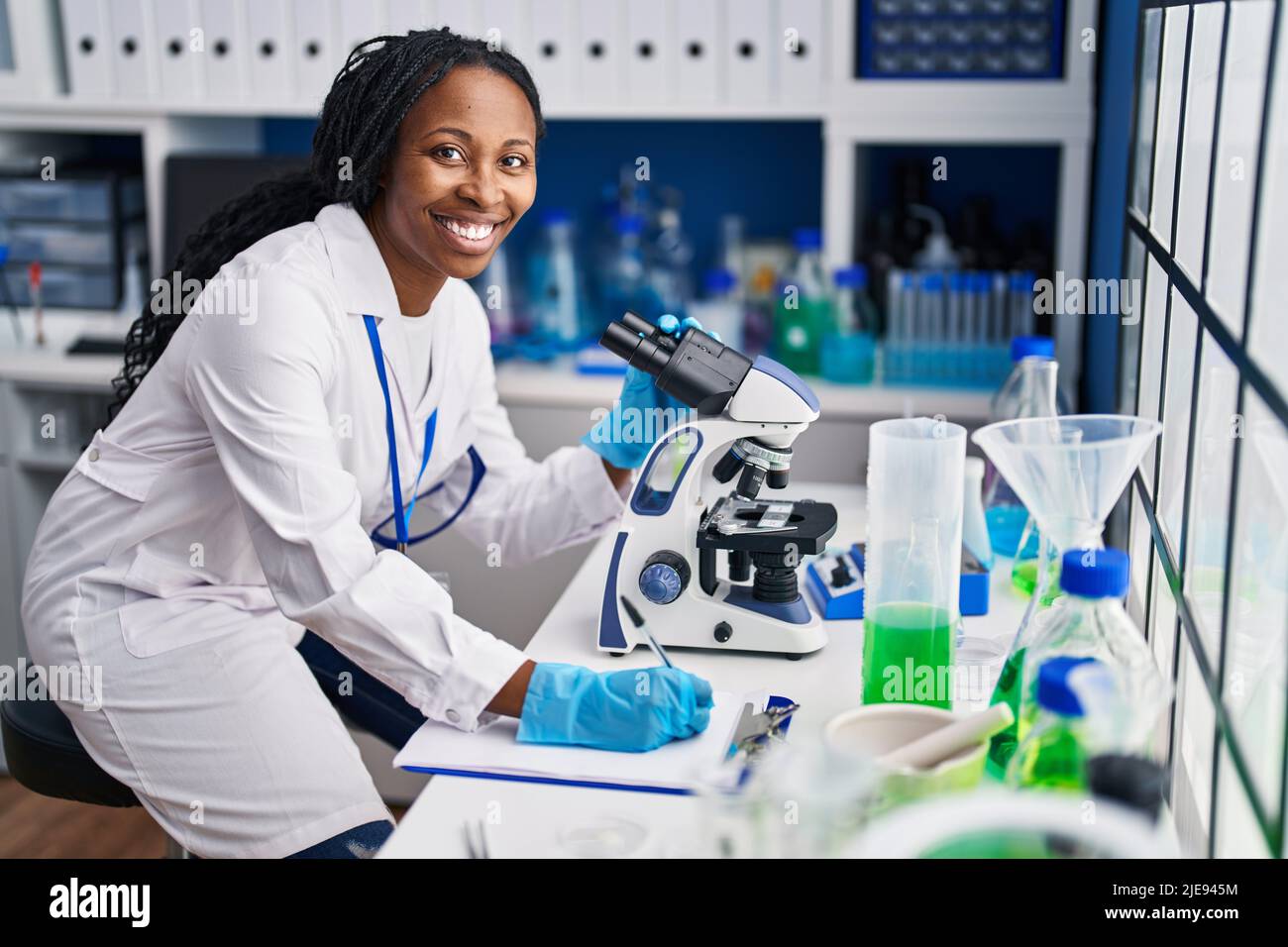 African American Woman Wearing Scientist Uniform Writing On Clipboard