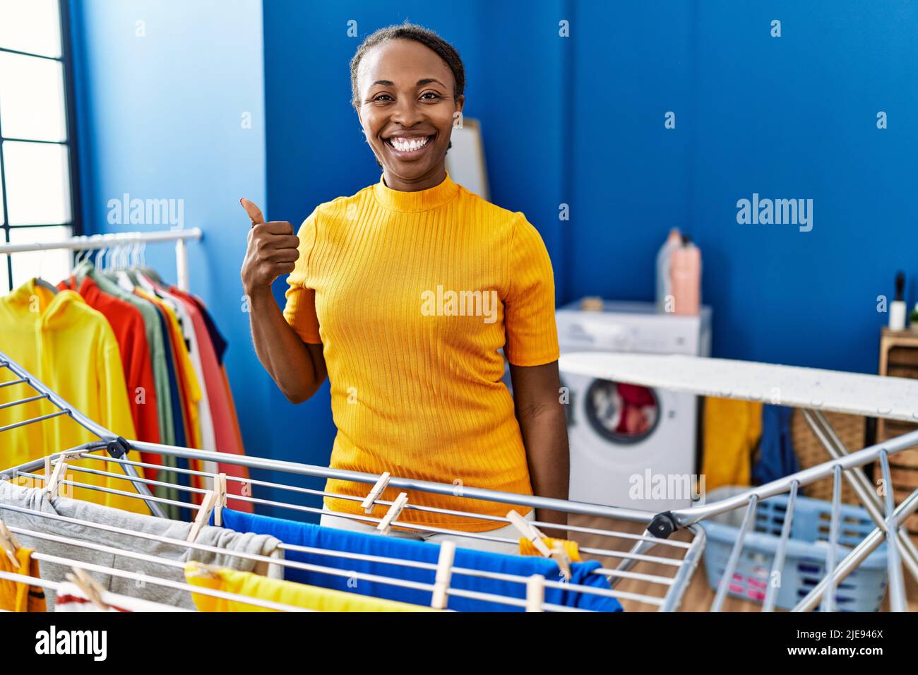 African woman hanging clothes at clothesline smiling happy and positive ...