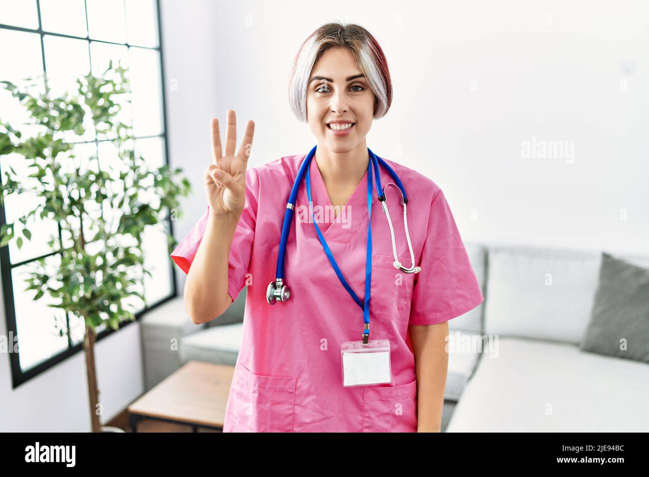 Young beautiful woman wearing doctor uniform and stethoscope showing and pointing up with ...