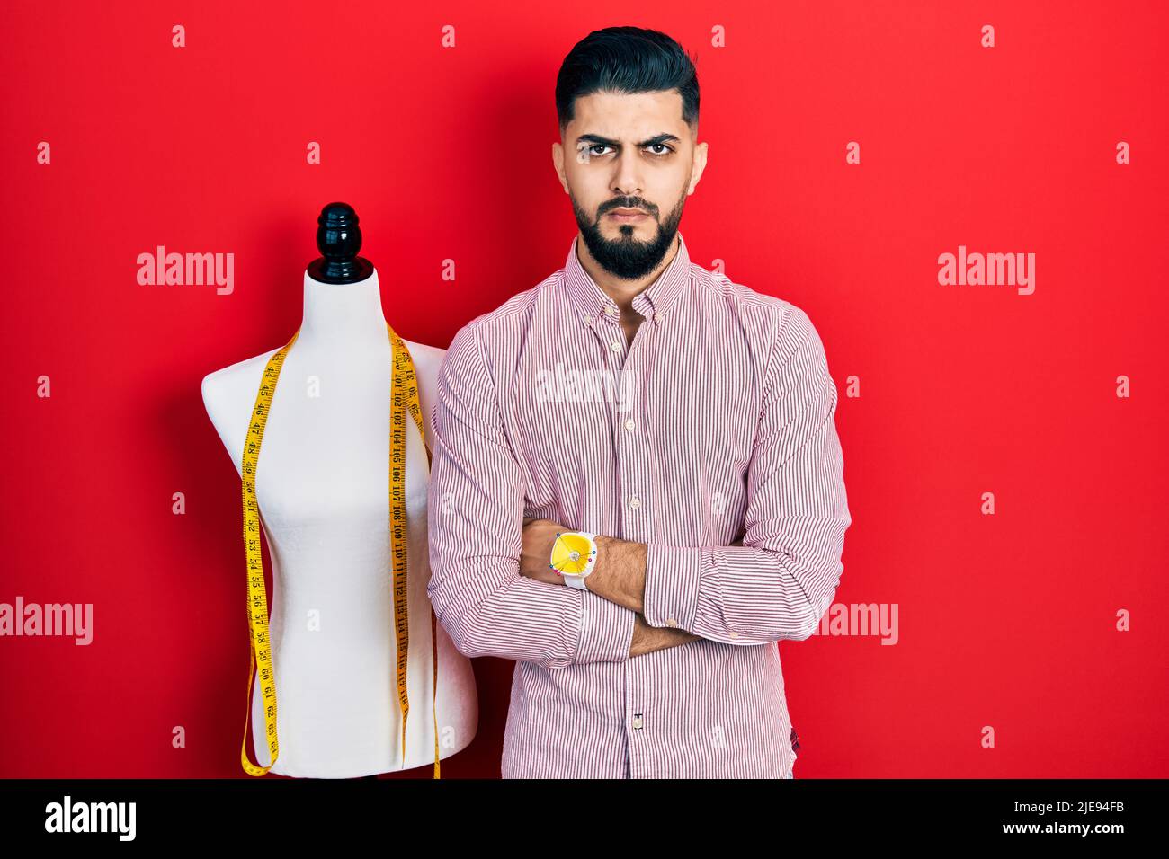 Handsome tailor man with beard with arms crossed gesture skeptic and ...