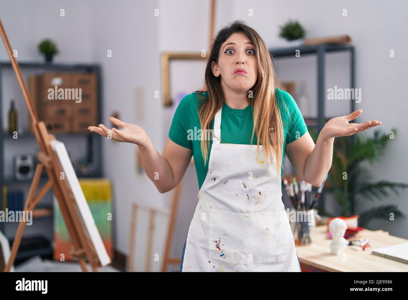 Young brunette woman at art studio shouting and screaming loud to side ...