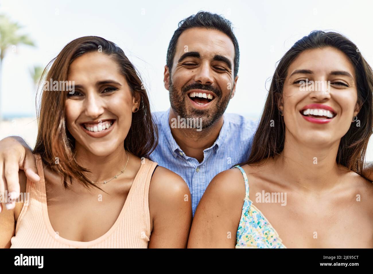 Three young hispanic friends smiling happy and hugging at the beach ...