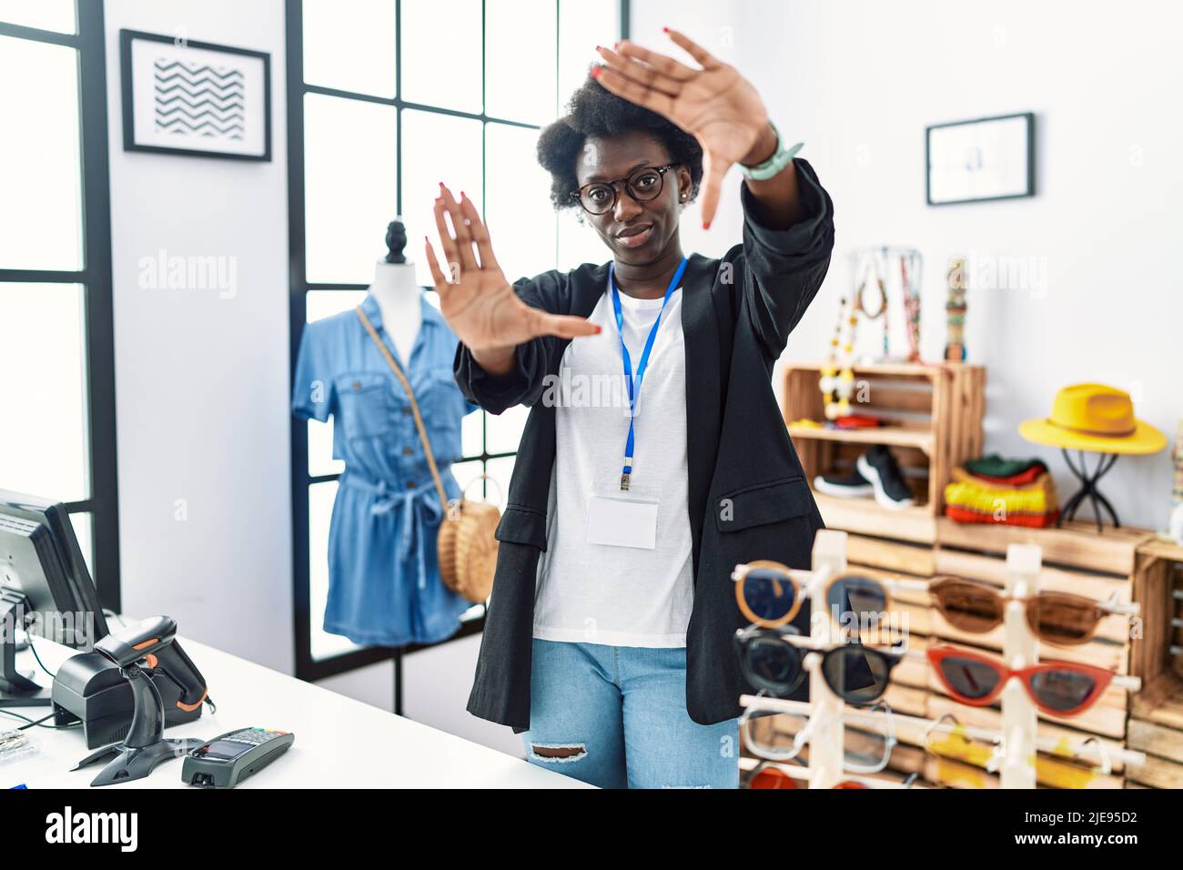 African young woman working as manager at retail boutique doing frame using hands palms and ...