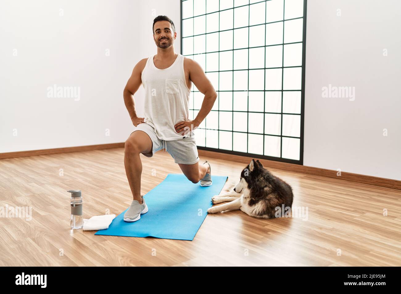 Young hispanic man smiling confident training yoga with dog at sport ...