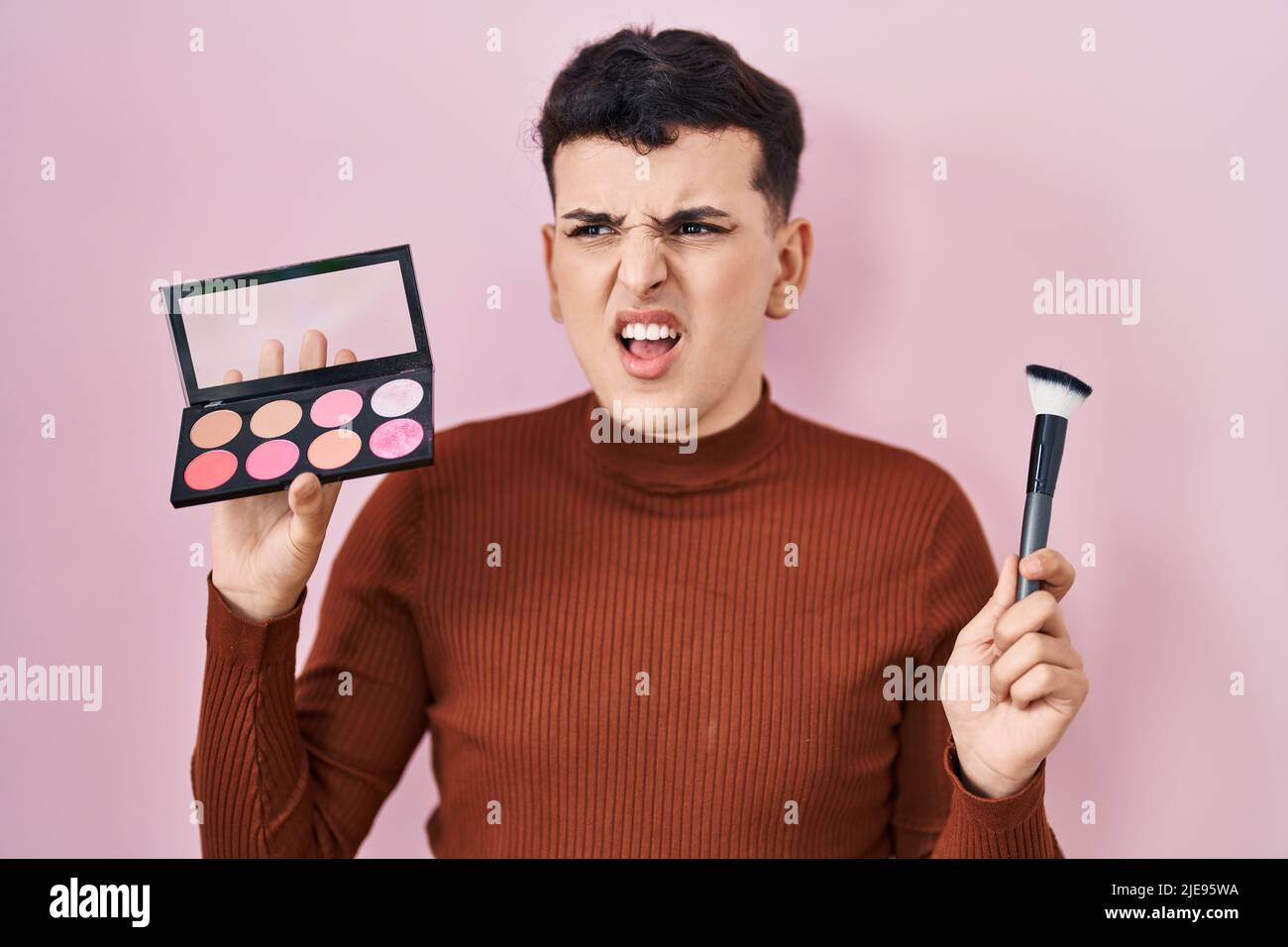Non binary person holding makeup brush and blush angry and mad ...