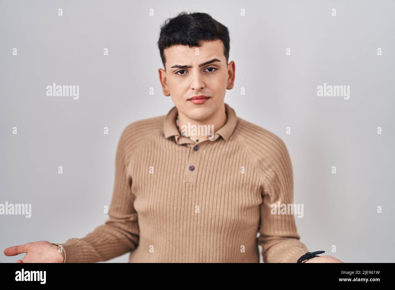 Non binary person standing over isolated background clueless and ...