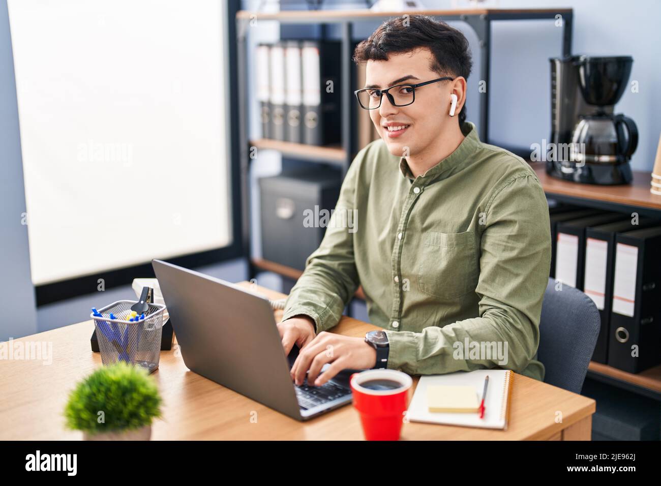 Young non binary man business worker using laptop listening to music at ...