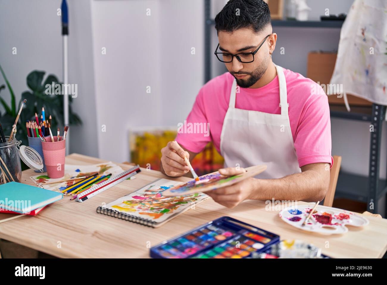 Young arab man artist drawing on notebook at art studio Stock Photo - Alamy