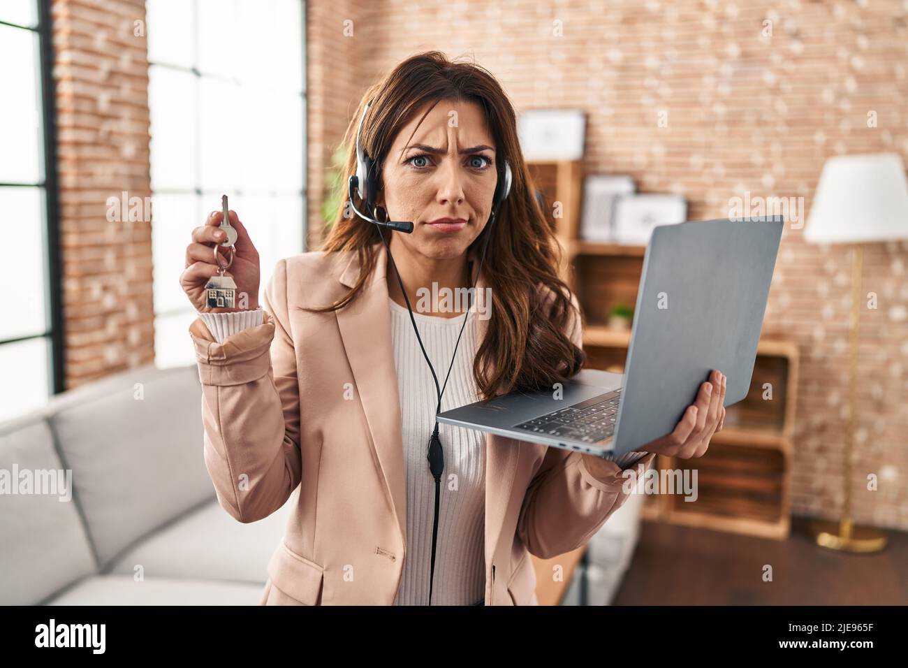 Young brunette woman working as real state agent holding keys of new ...