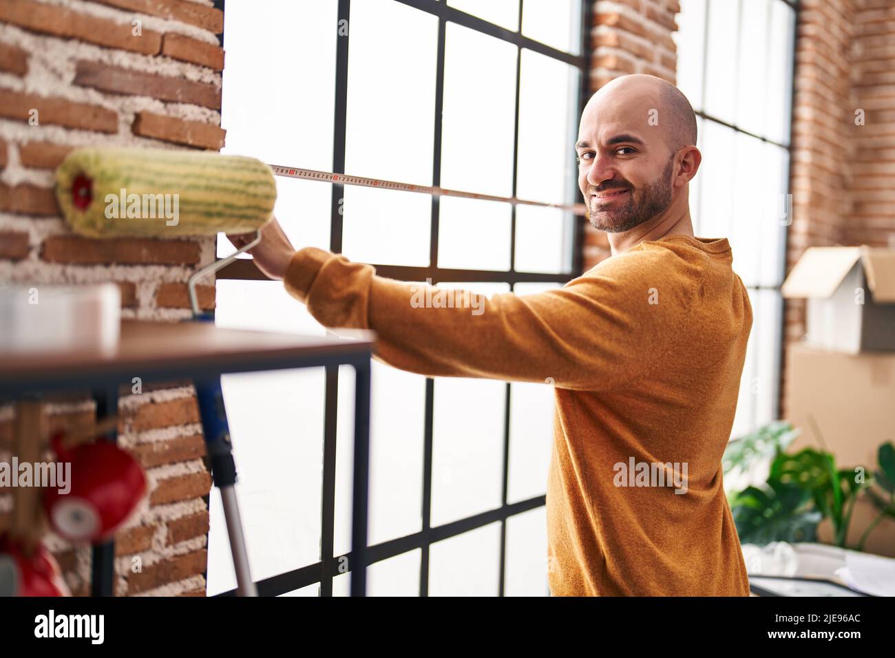 Young man smiling confident measuring window at new home Stock Photo ...