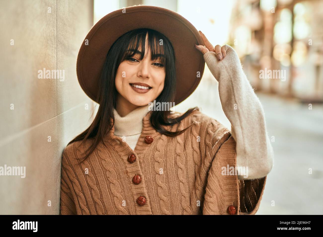 Brunette woman wearing winter hat smiling leaning on the wall Stock ...