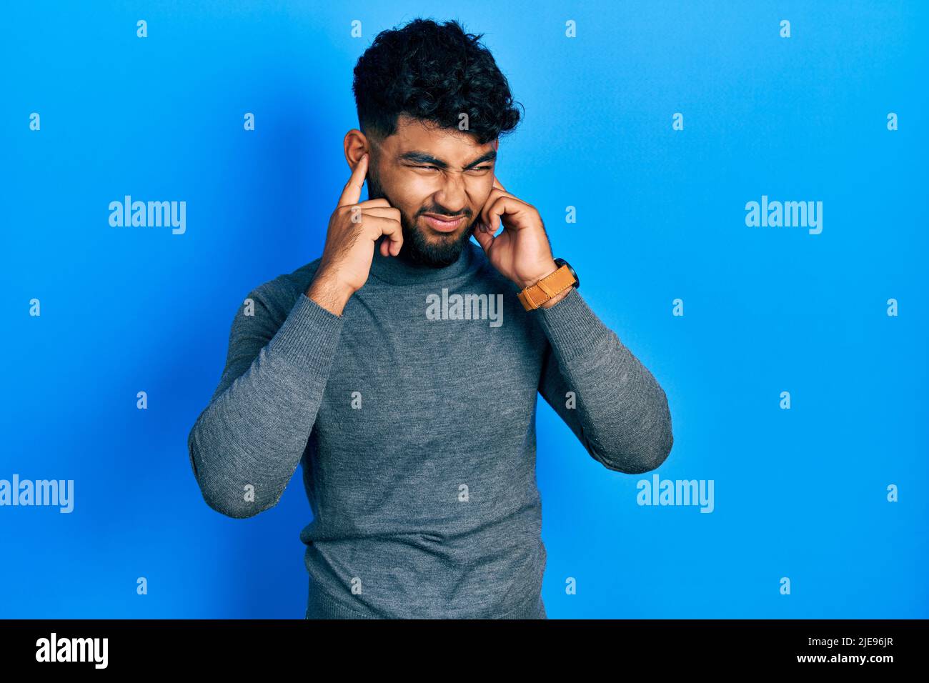 Arab man with beard wearing turtleneck sweater covering ears with ...