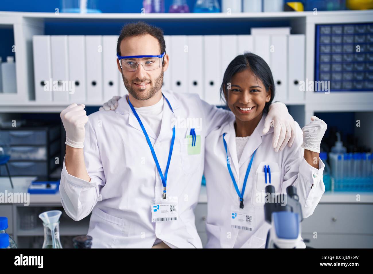 Interracial couple working at scientist laboratory screaming proud ...