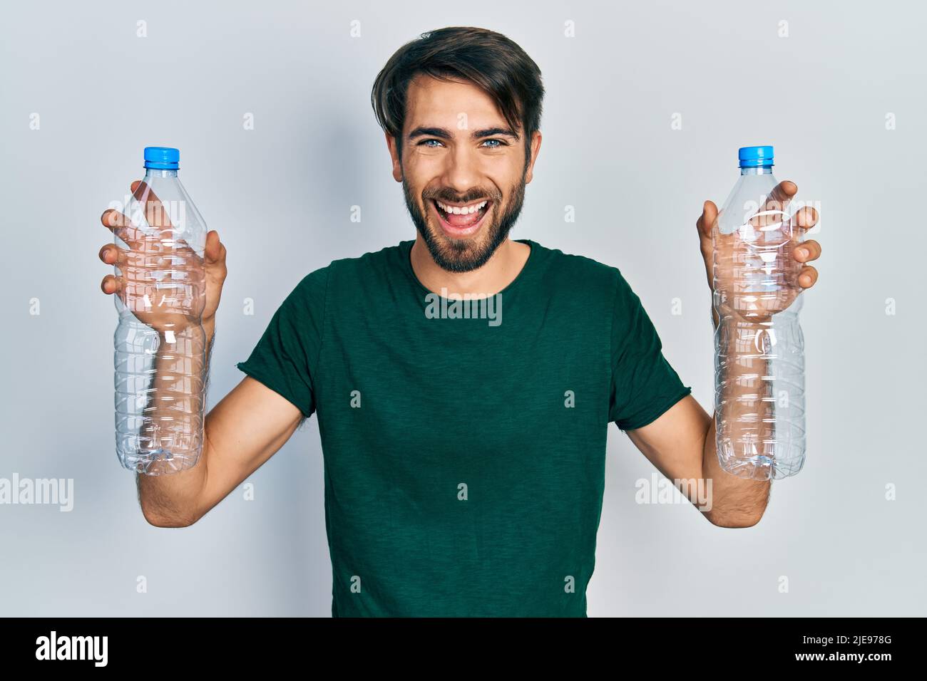 Young hispanic man holding recycling plastic bottles smiling and ...