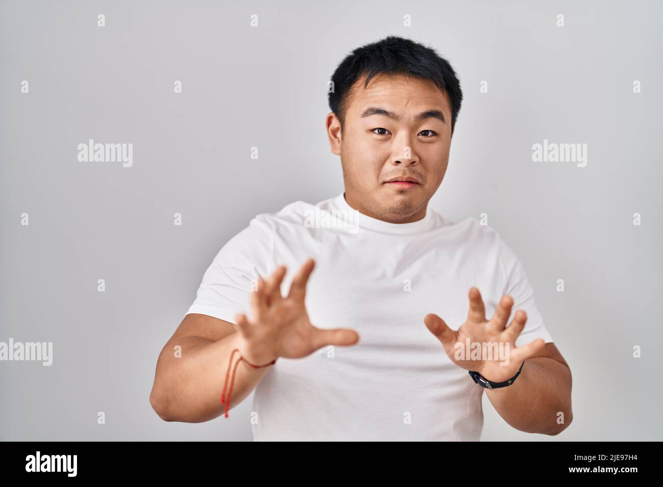 Young chinese man standing over white background afraid and terrified ...