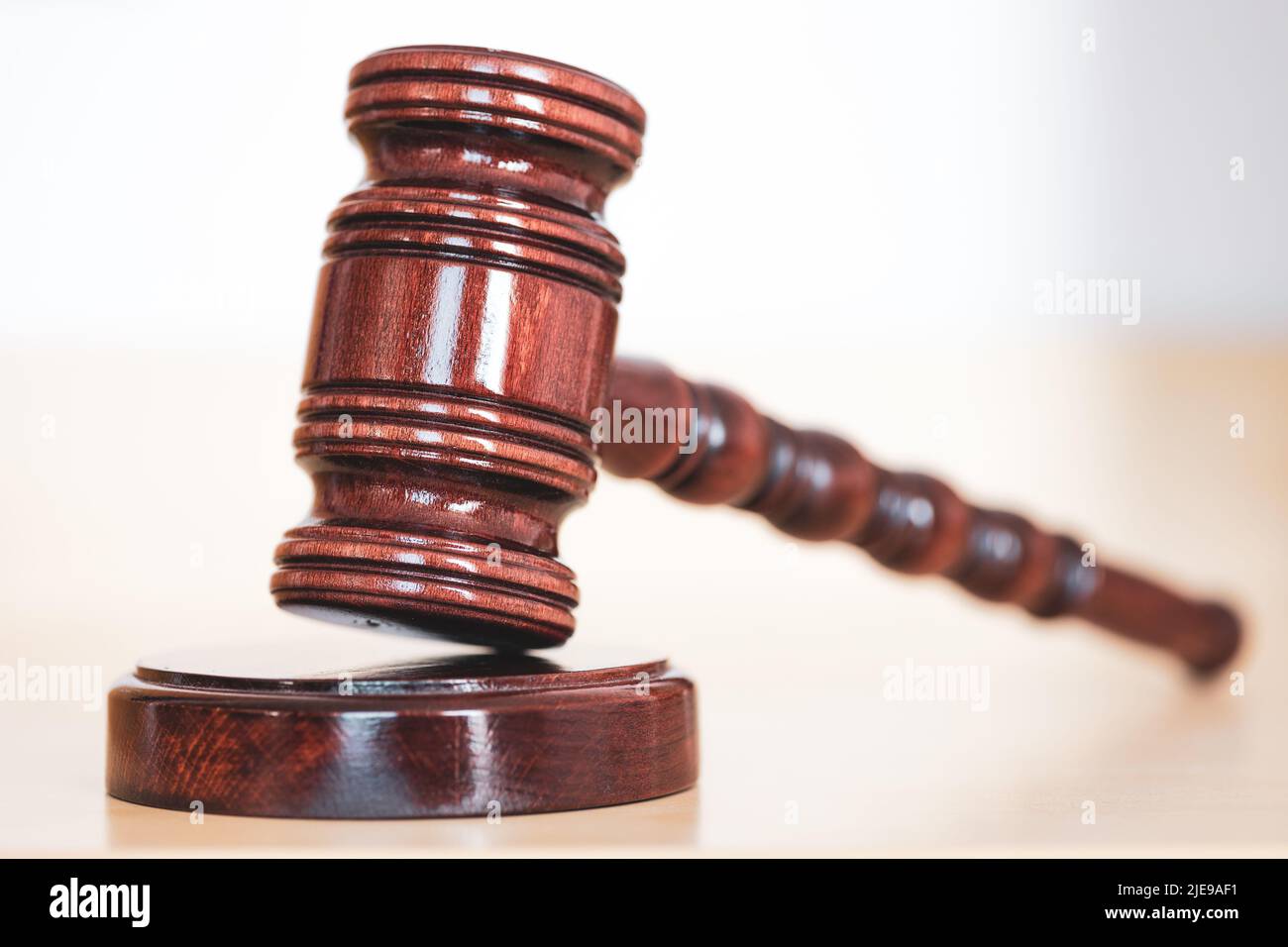 Judges wooden gavel resting on a wooden plinth on a table in court ...