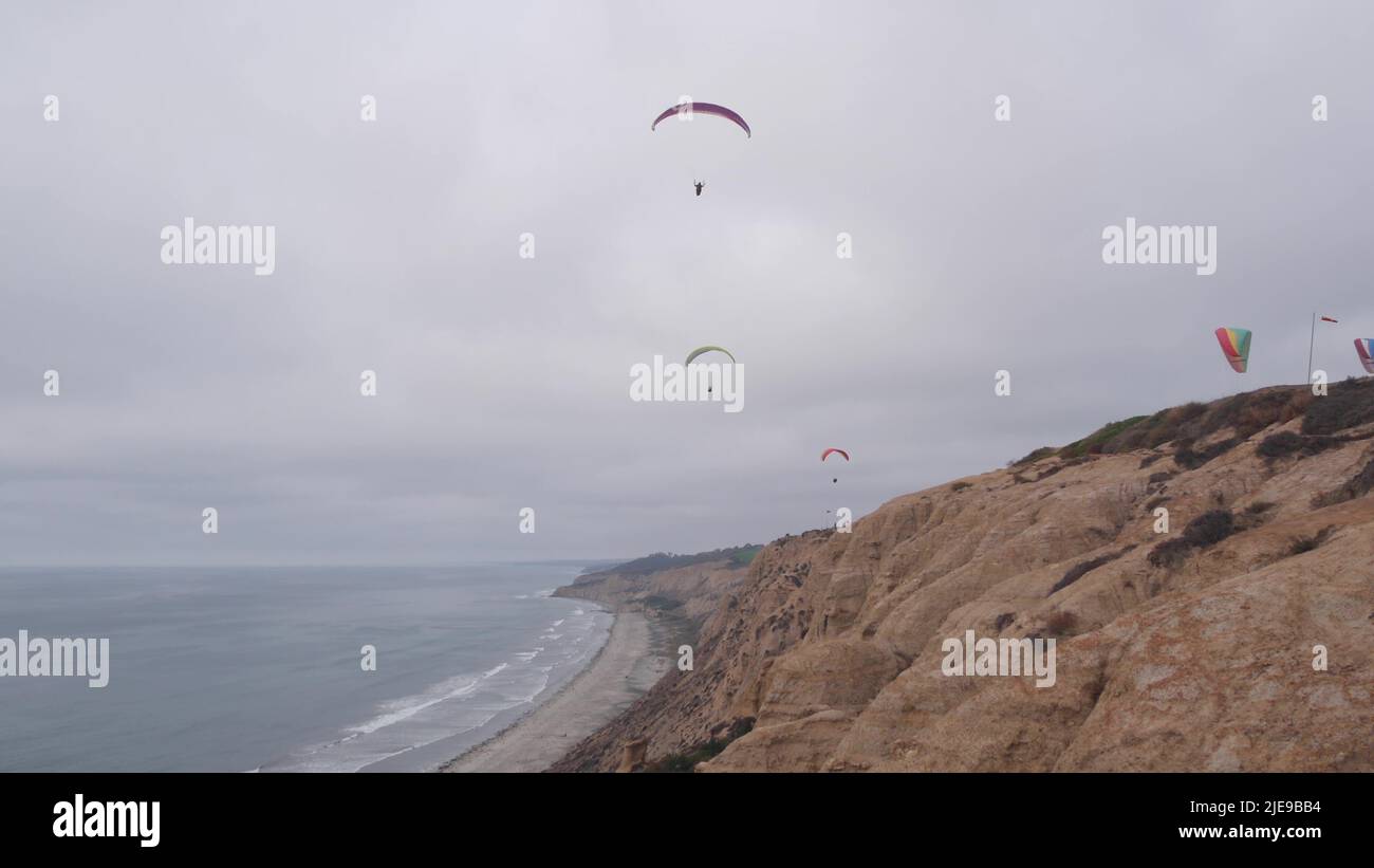 People paragliding, Torrey Pines cliff or bluff. Paraglider soaring in ...