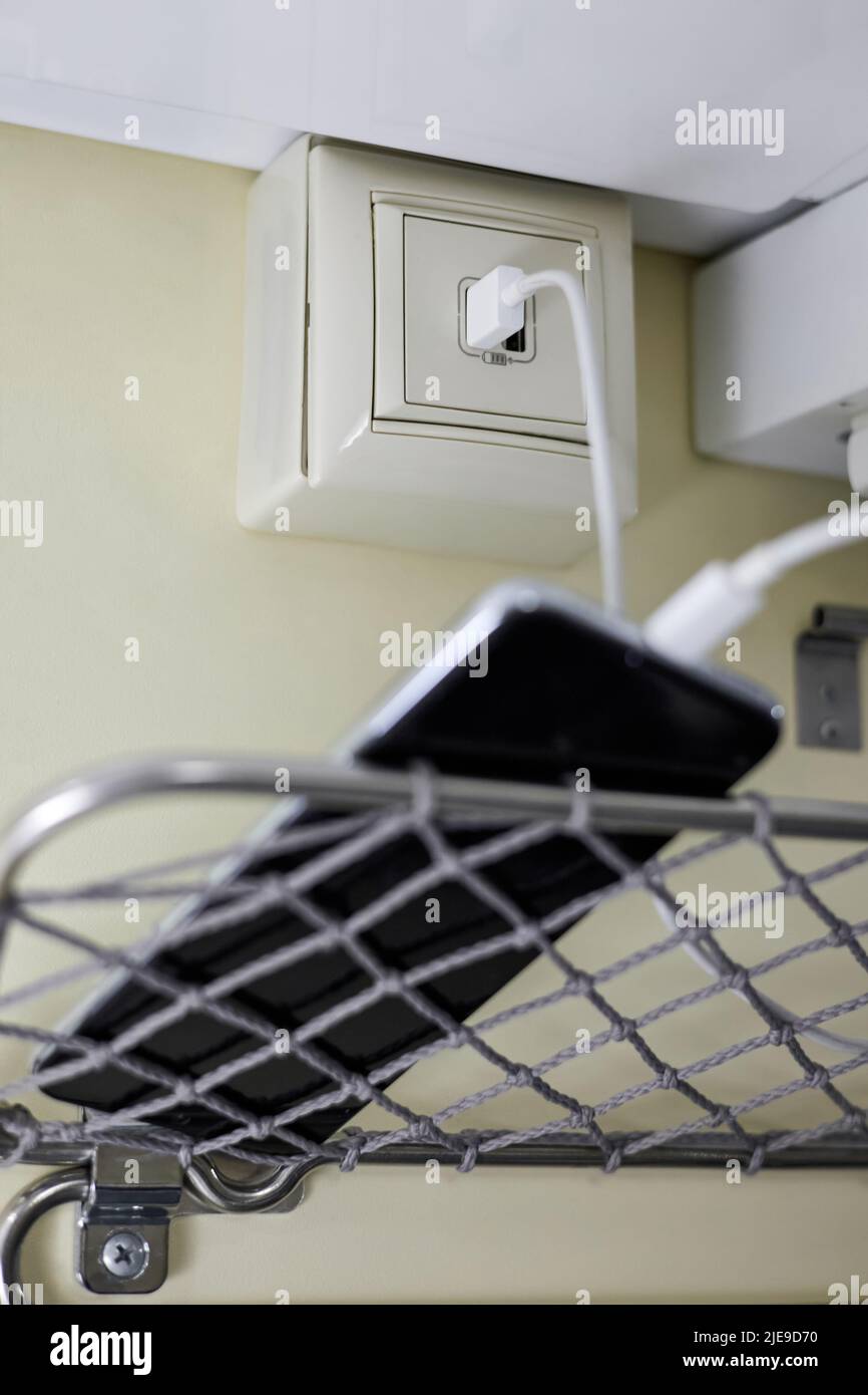 A smartphone is charging in a compartment car of a passenger train ...