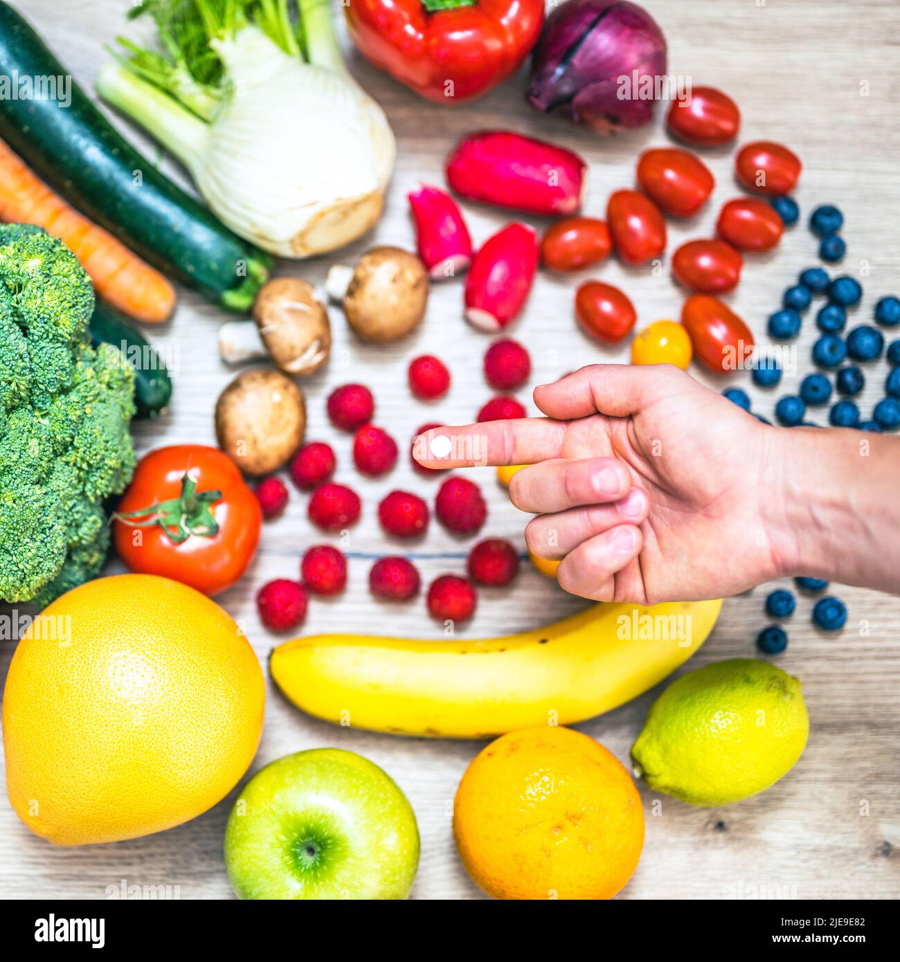 Hand is holding food supplement tabletts over a wooden table full of ...
