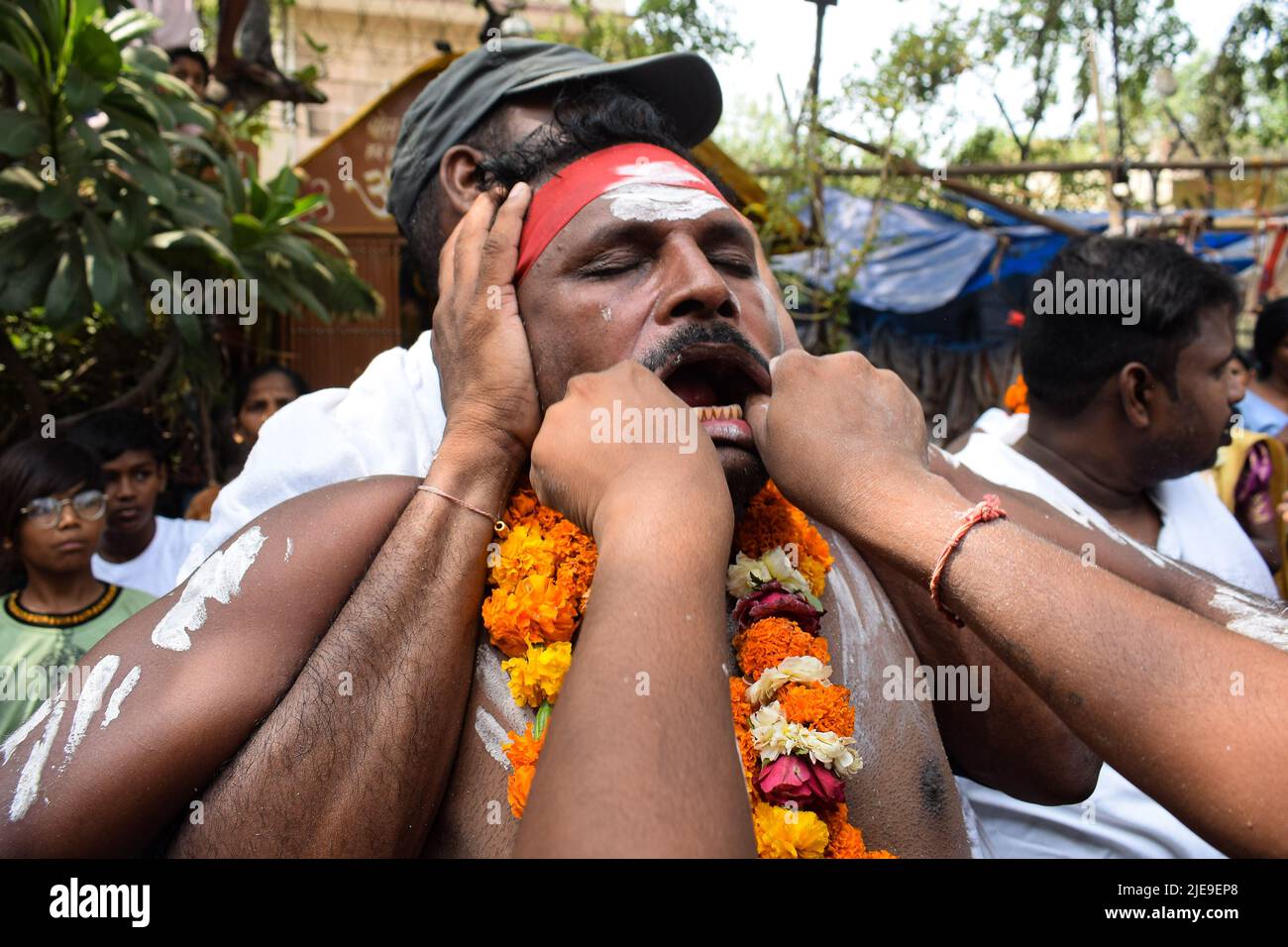 New Delhi, India. 26th June, 2022. A temple priest pulls the cheeks of ...