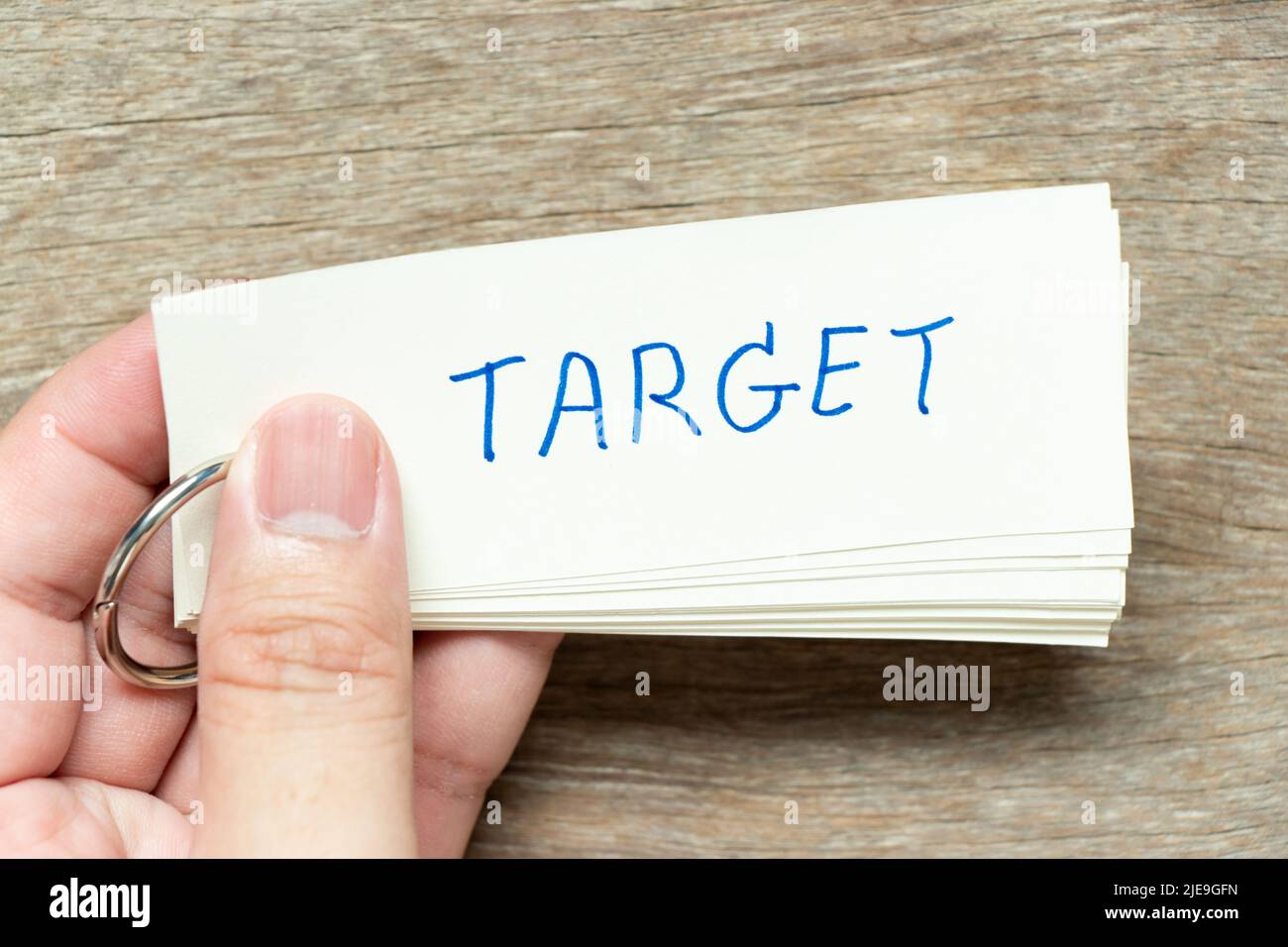 Man hold the flash card with handwriting word target on wood background ...