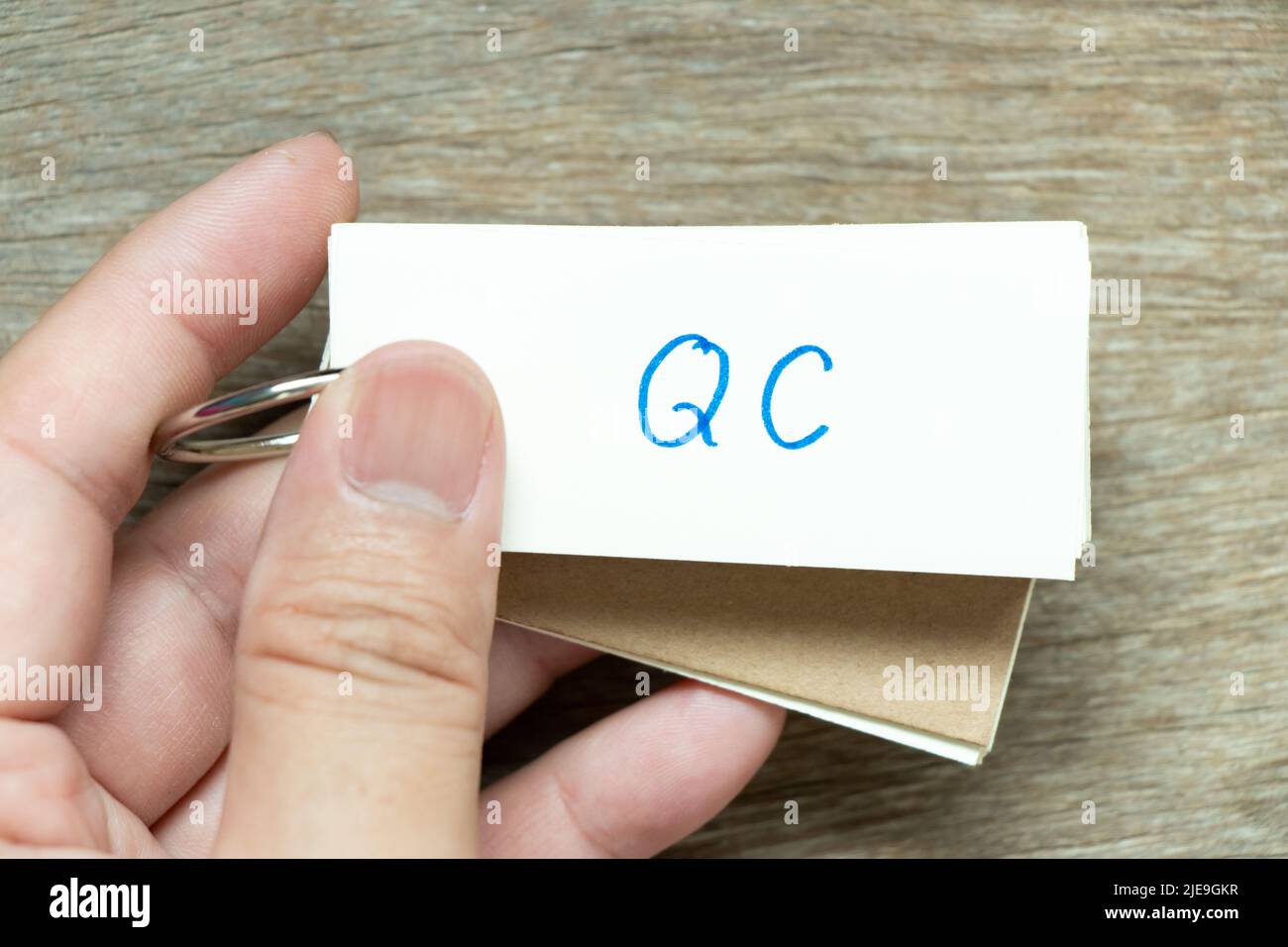 Man hold the flash card with handwriting word QC (Abbreviation of ...