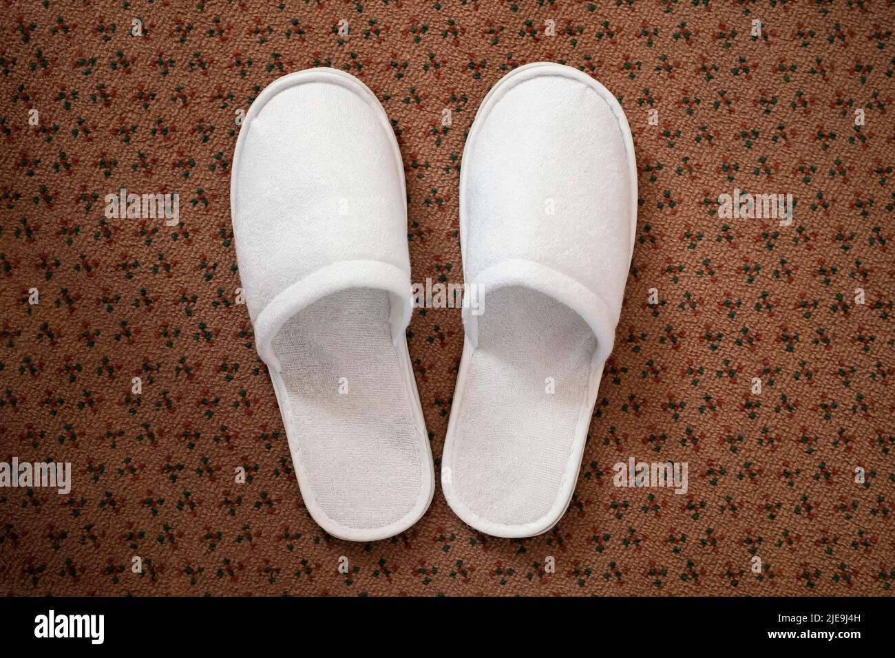 White slippers on the carpet in the hotel room. Top view Stock Photo ...