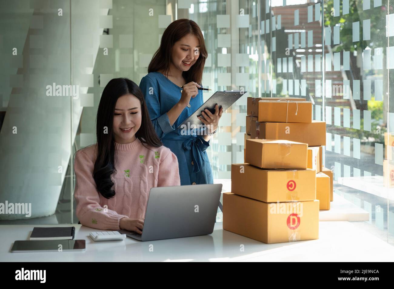 Young women teamwork partners packing order into box together using ...
