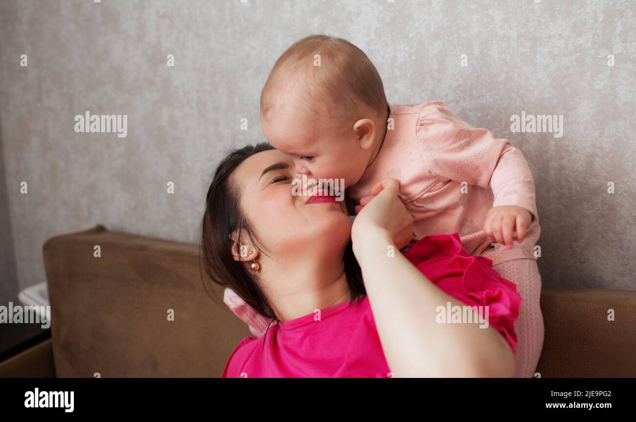 Cute little girl bites her mother's nose Stock Photo - Alamy