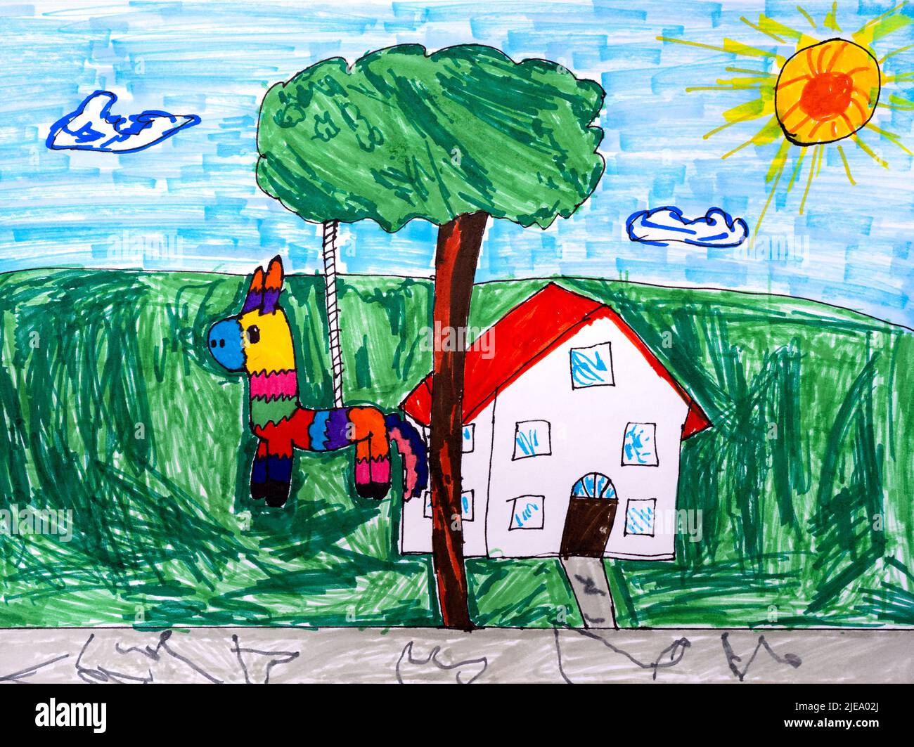 A pinata hanging of a tree in front of a white house. There is a green ...