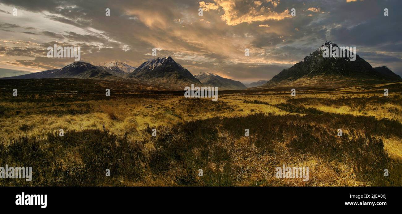 Scottish snow topped mountain range with grasslands and sunset sky's ...