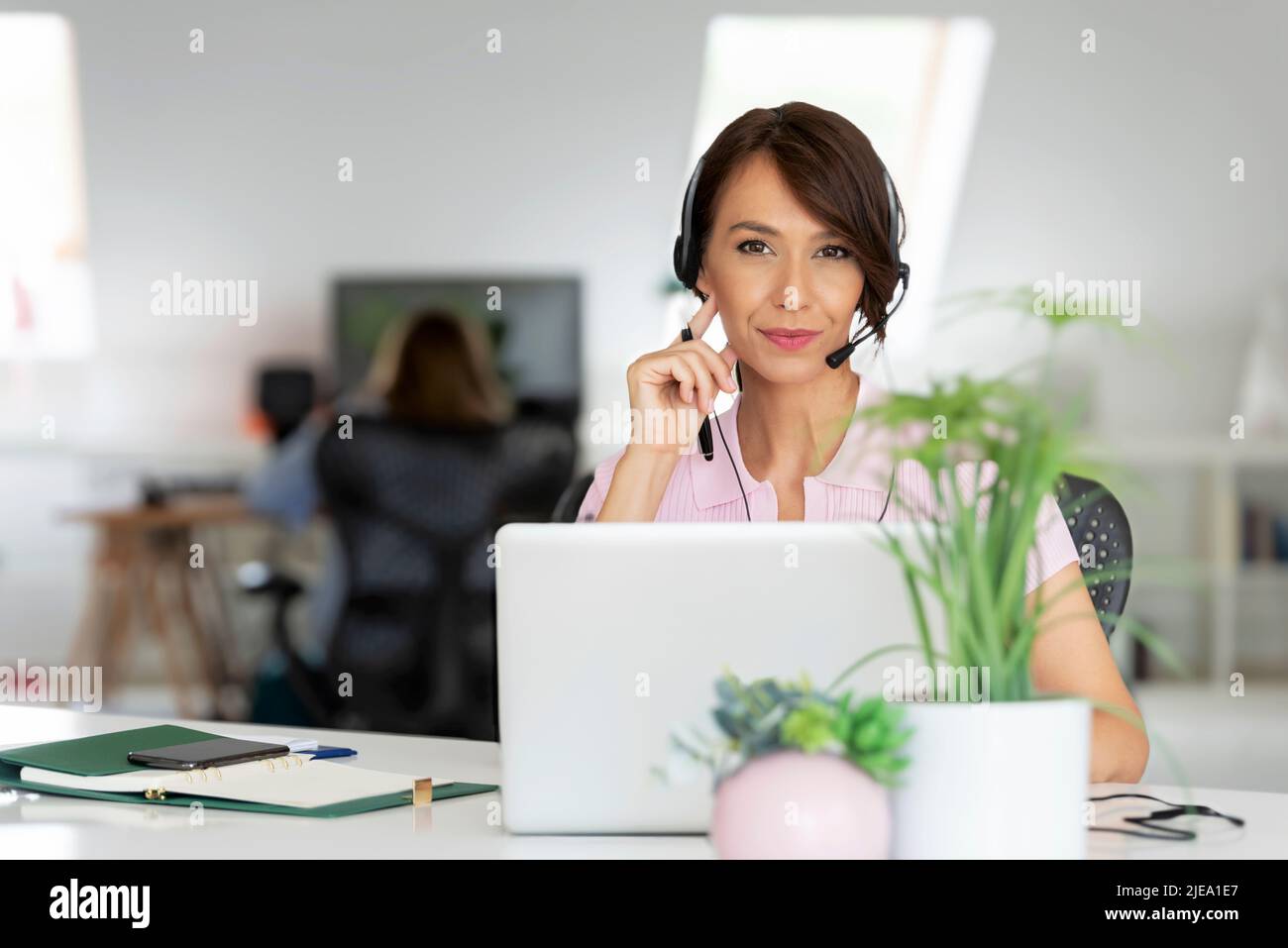 Customer service assistant wearing headset while sitting behind her ...