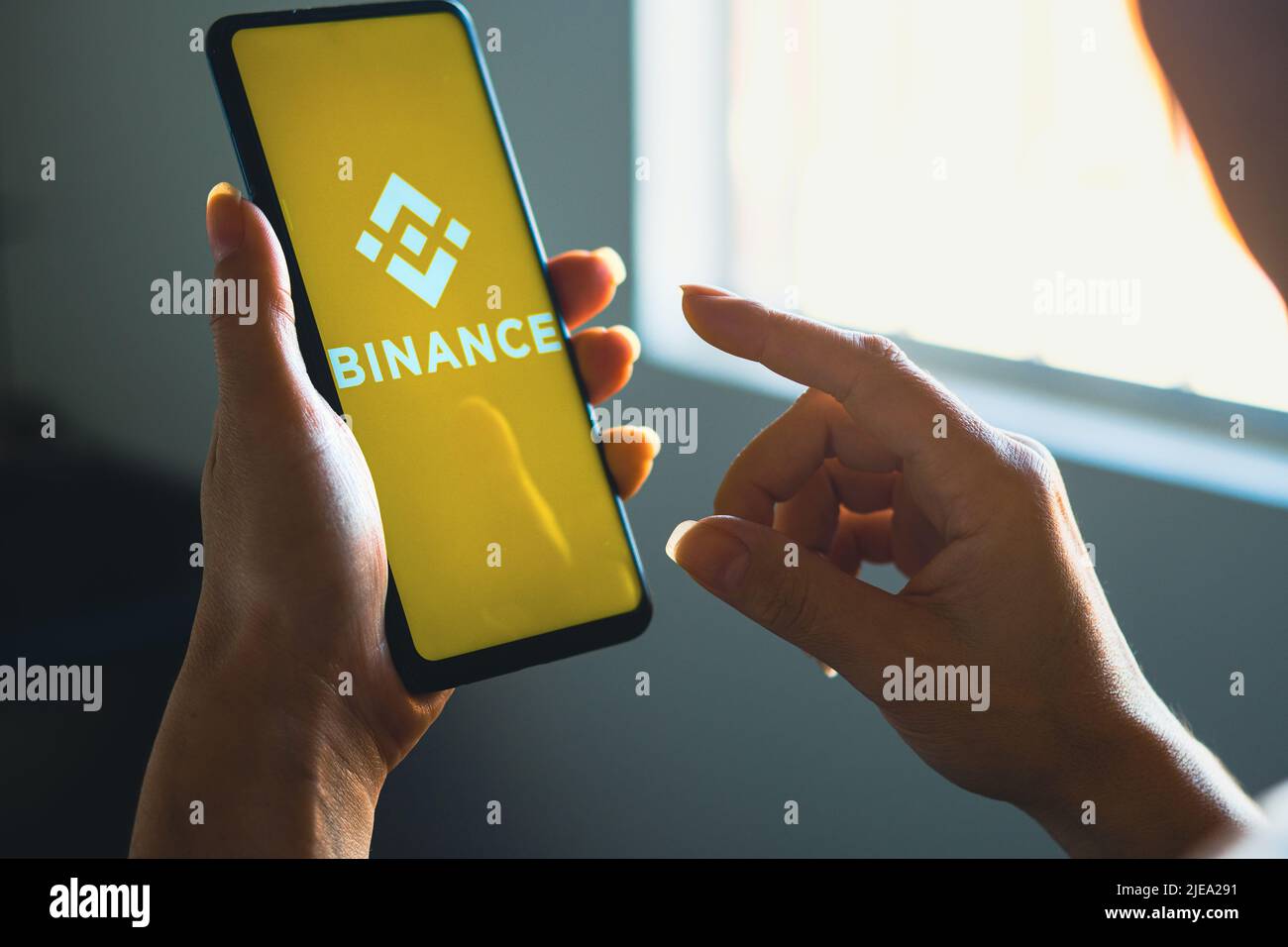 In this photo illustration, a woman holds a smartphone with the Binance ...