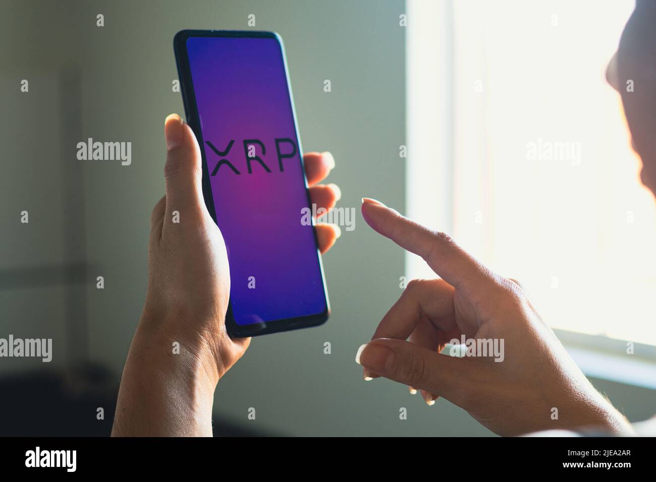 In this photo illustration, a woman holds a smartphone with the Ripple ...