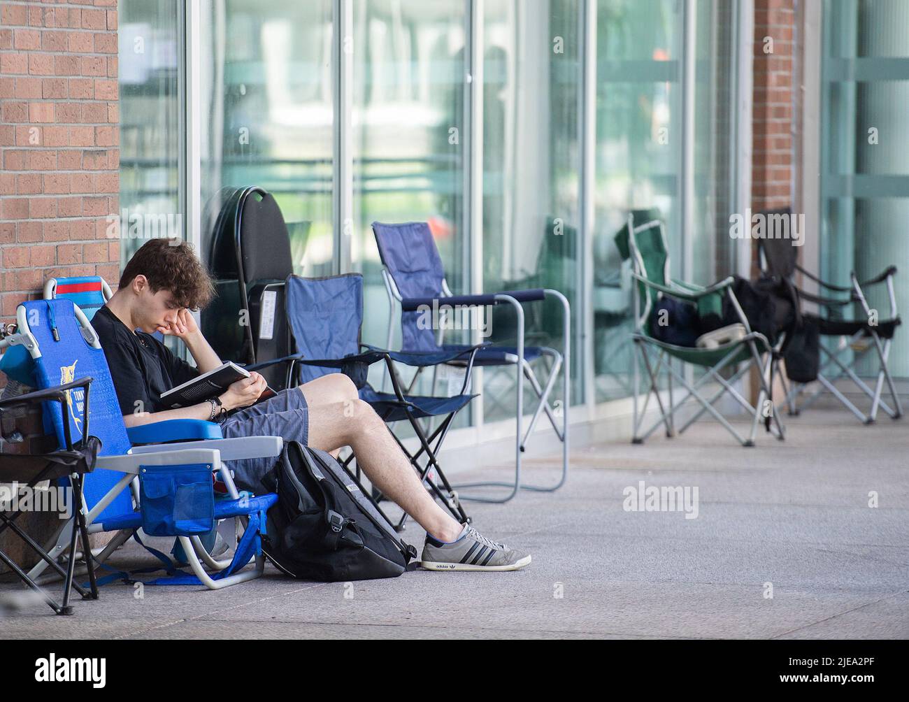 A man reads as he waits in line outside the Guy Favreau federal ...
