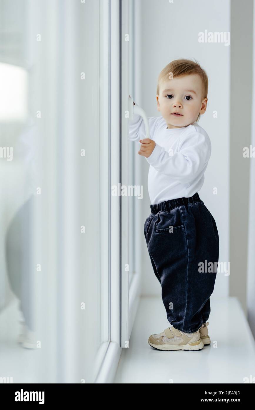 Portrait of white Caucasian child boy at home looking out of window ...